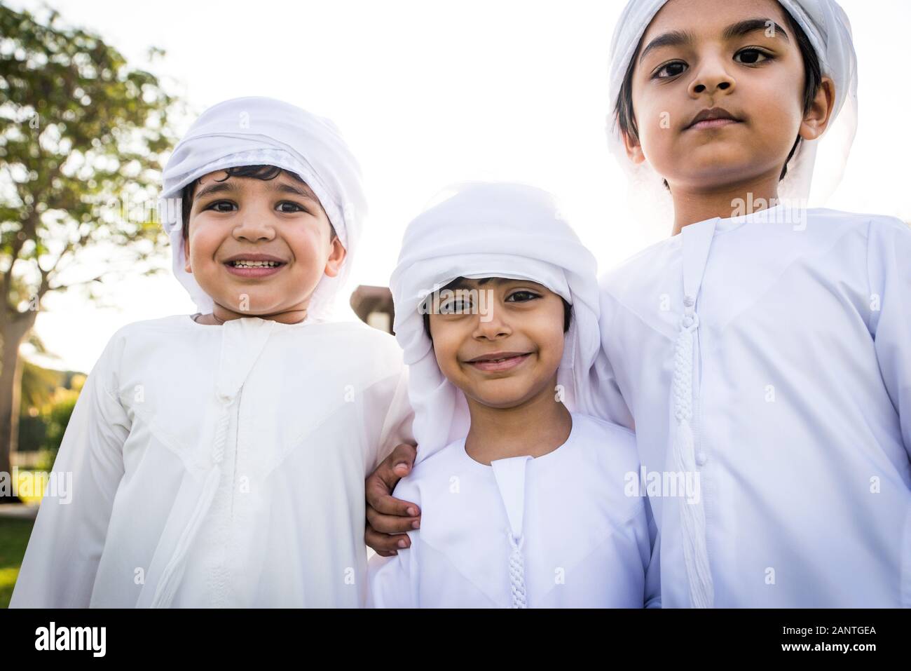 Group of middle-eastern kids wearing white kandora playing in a park in ...