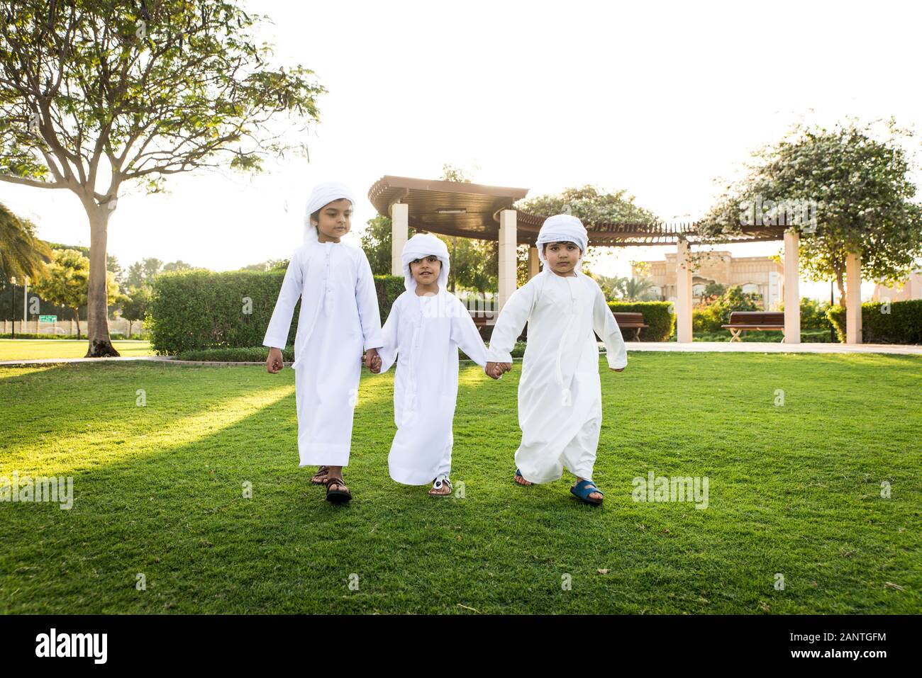 Group of middle-eastern kids wearing white kandora playing in a park in ...