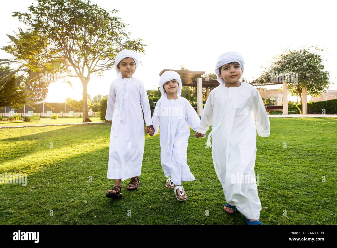 Group of middle-eastern kids wearing white kandora playing in a park in ...