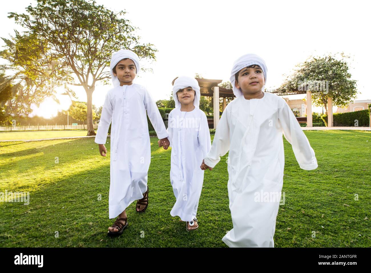 Group of middle-eastern kids wearing white kandora playing in a park in ...