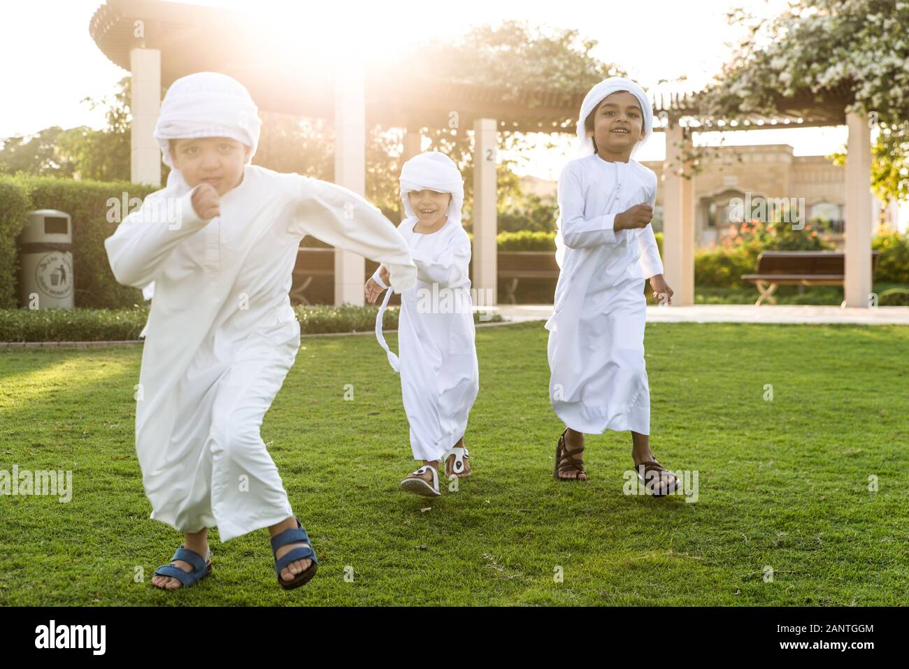 Group of middle-eastern kids wearing white kandora playing in a park in ...
