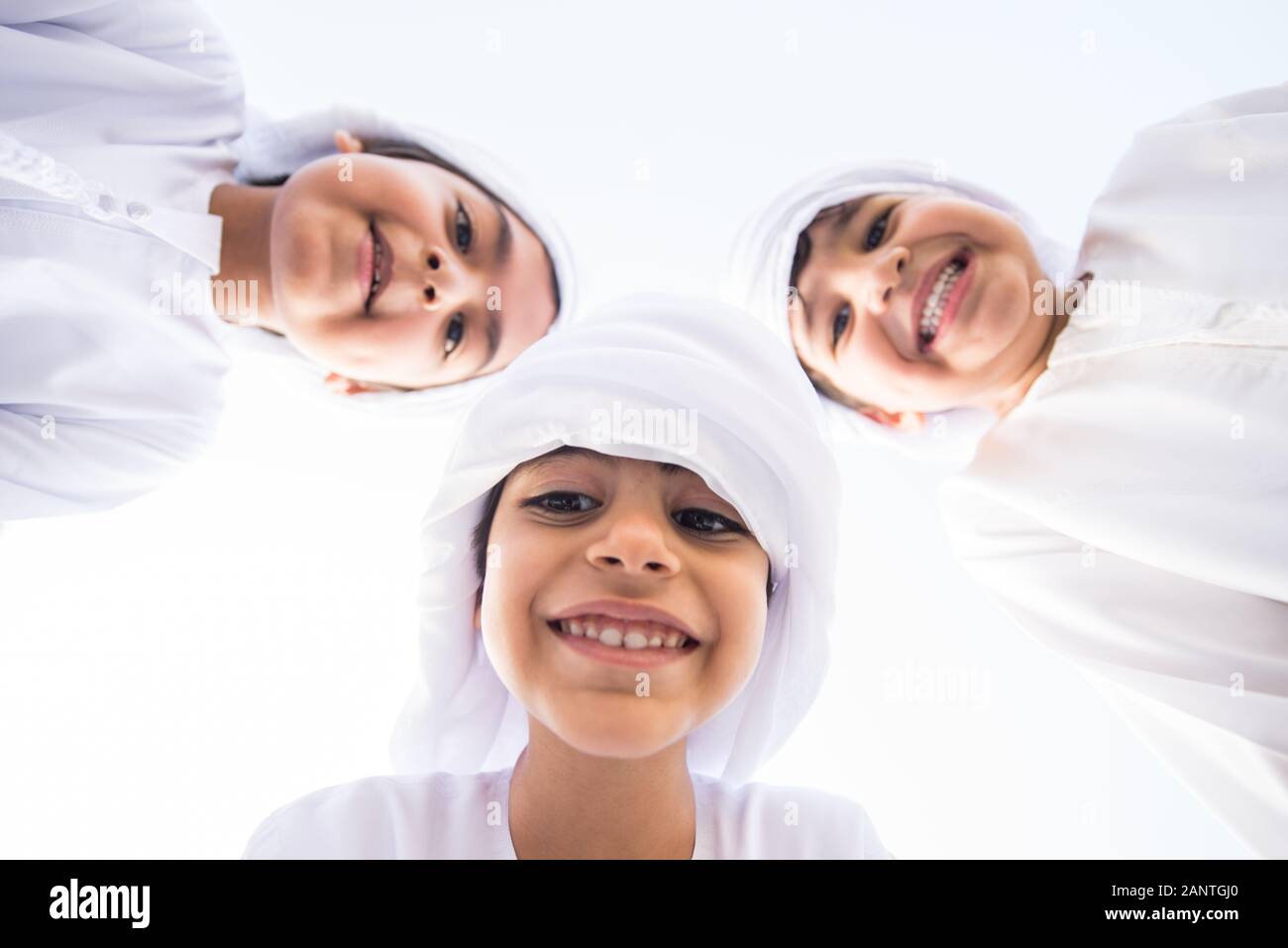 Group of middle-eastern kids wearing white kandora playing in a park in ...