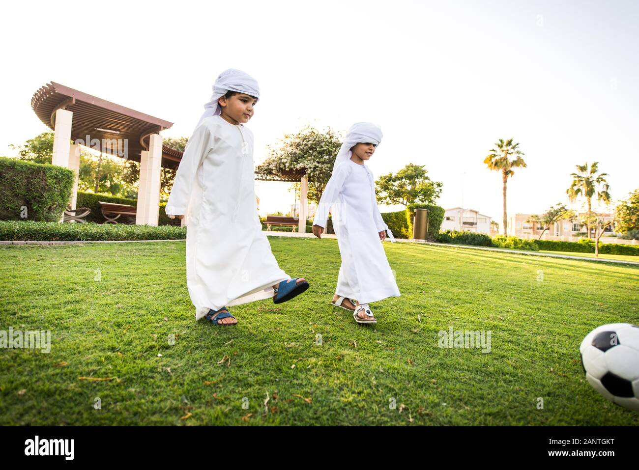 Group of middle-eastern kids wearing white kandora playing in a park in ...