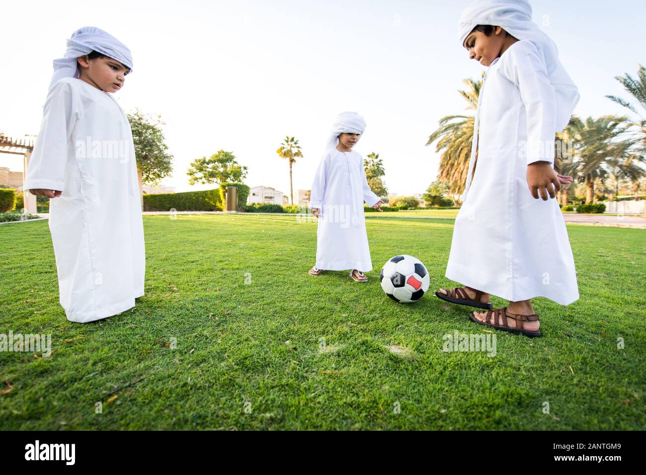 Group of middle-eastern kids wearing white kandora playing in a park in ...