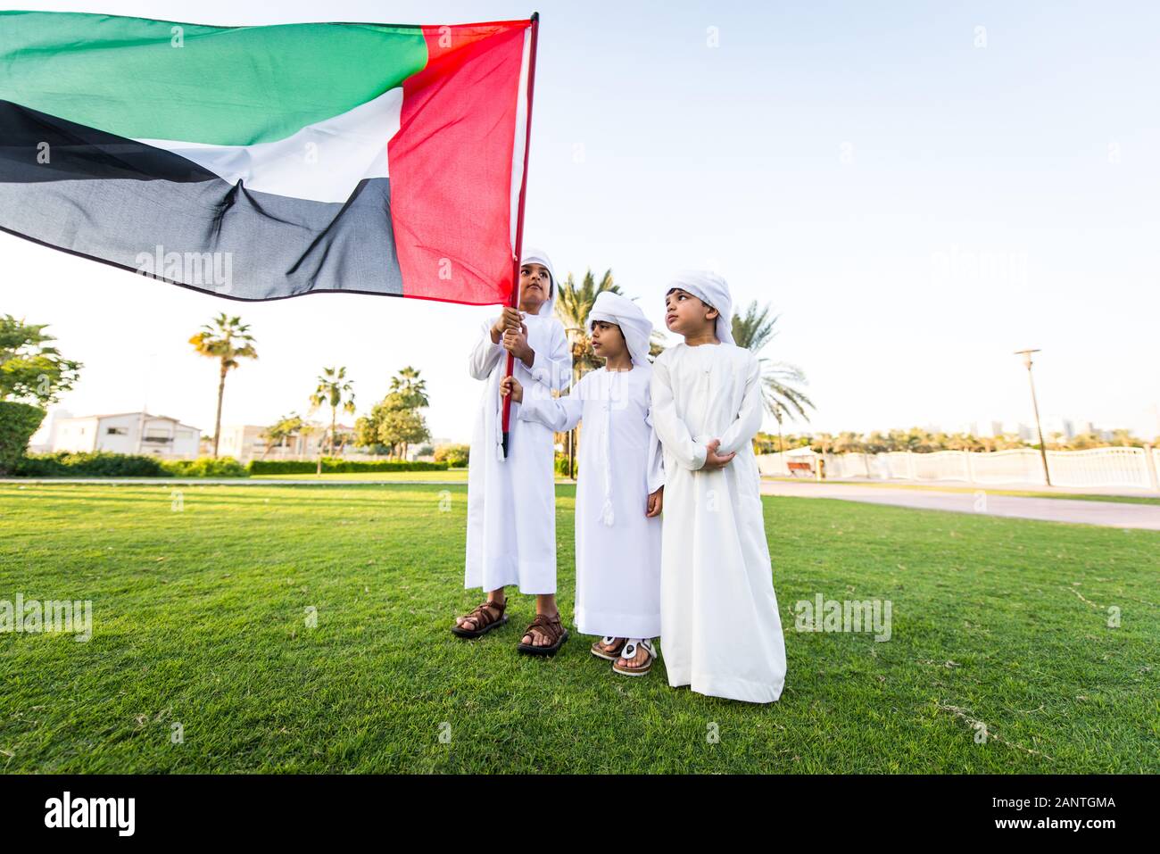 Group of middle-eastern kids wearing white kandora playing in a park in ...