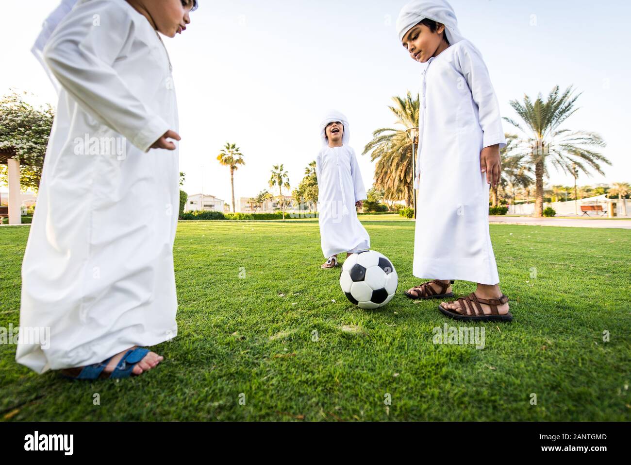 Group of middle-eastern kids wearing white kandora playing in a park in ...