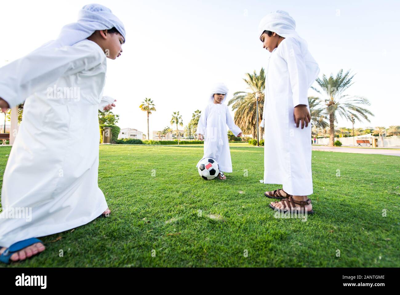 Group of middle-eastern kids wearing white kandora playing in a park in ...