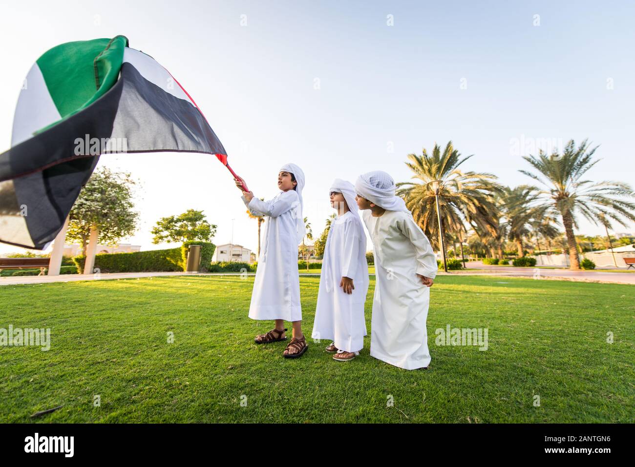 Group of middle-eastern kids wearing white kandora playing in a park in ...