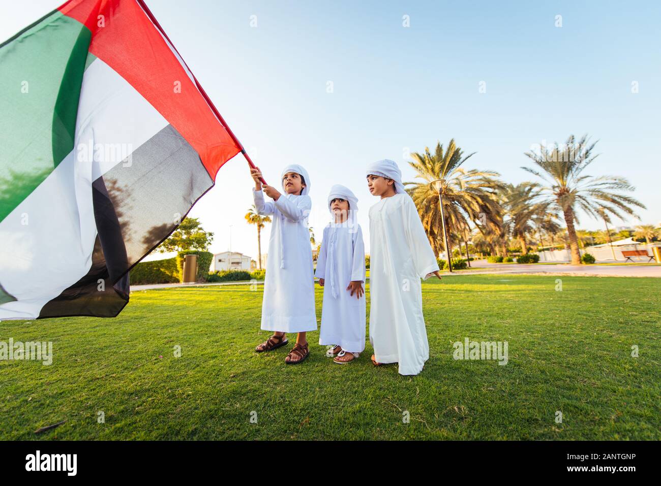Group of middle-eastern kids wearing white kandora playing in a park in ...