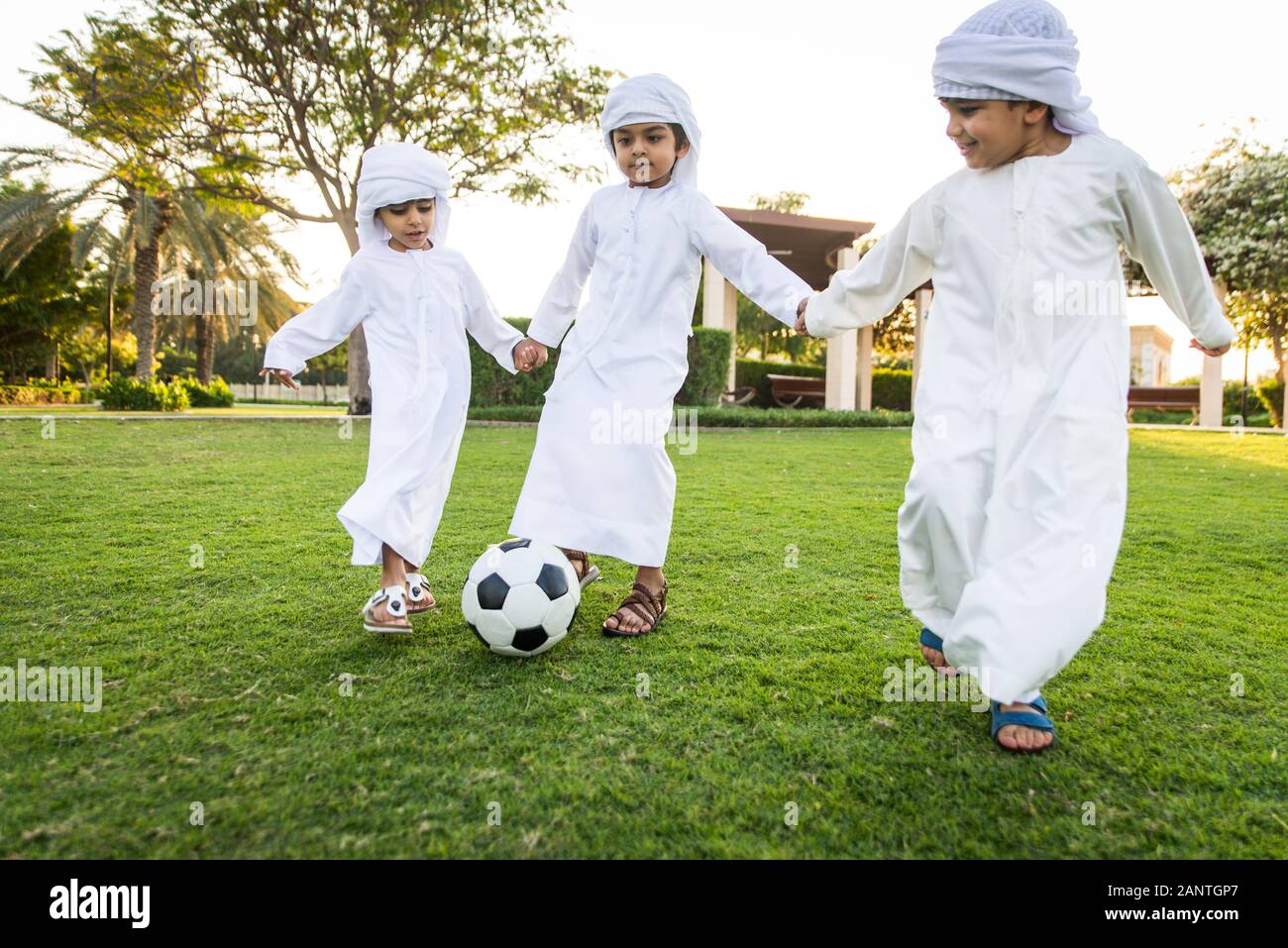 Group of middle-eastern kids wearing white kandora playing in a park in ...