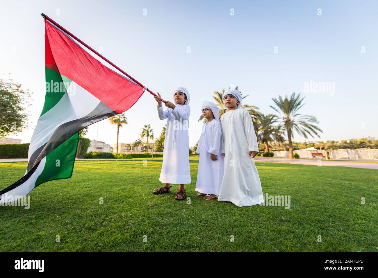 Group of middle-eastern kids wearing white kandora playing in a park in ...