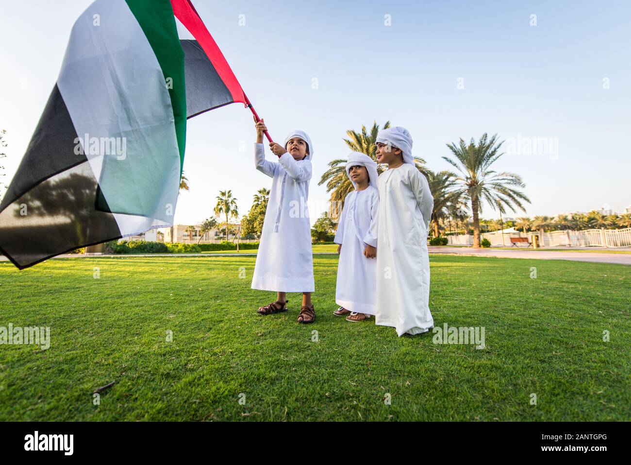 Group of middle-eastern kids wearing white kandora playing in a park in ...