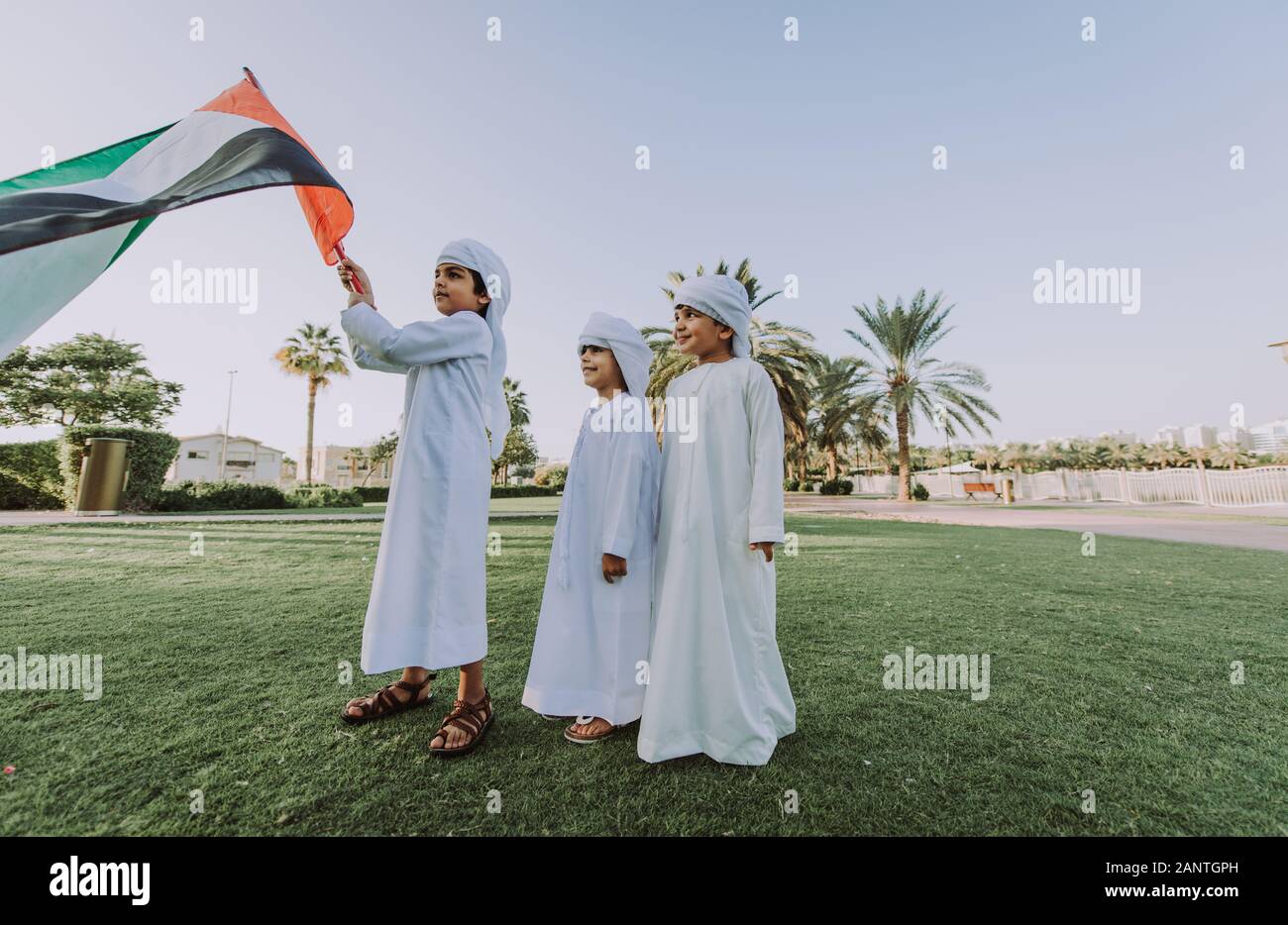 Group of middle-eastern kids wearing white kandora playing in a park in ...