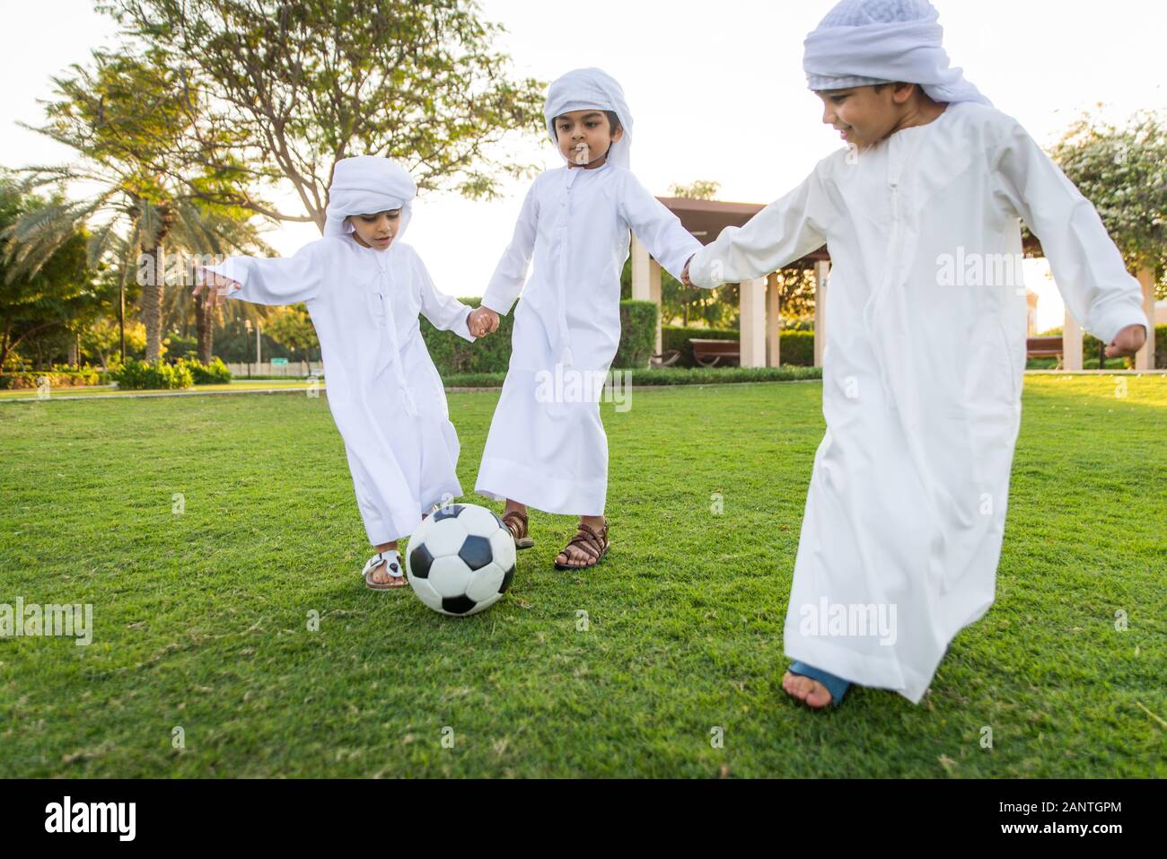 Group of middle-eastern kids wearing white kandora playing in a park in ...