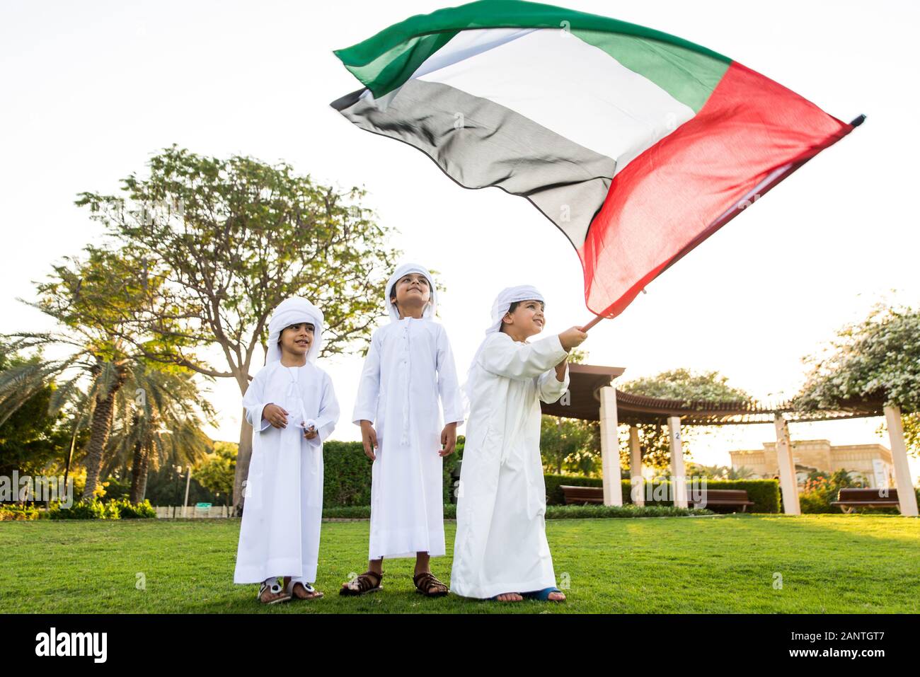 Group of middle-eastern kids wearing white kandora playing in a park in ...