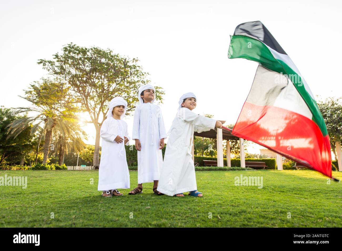 Group of middle-eastern kids wearing white kandora playing in a park in ...