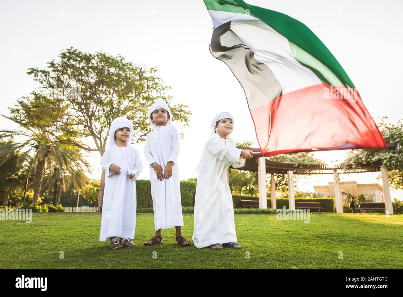 Group of middle-eastern kids wearing white kandora playing in a park in ...