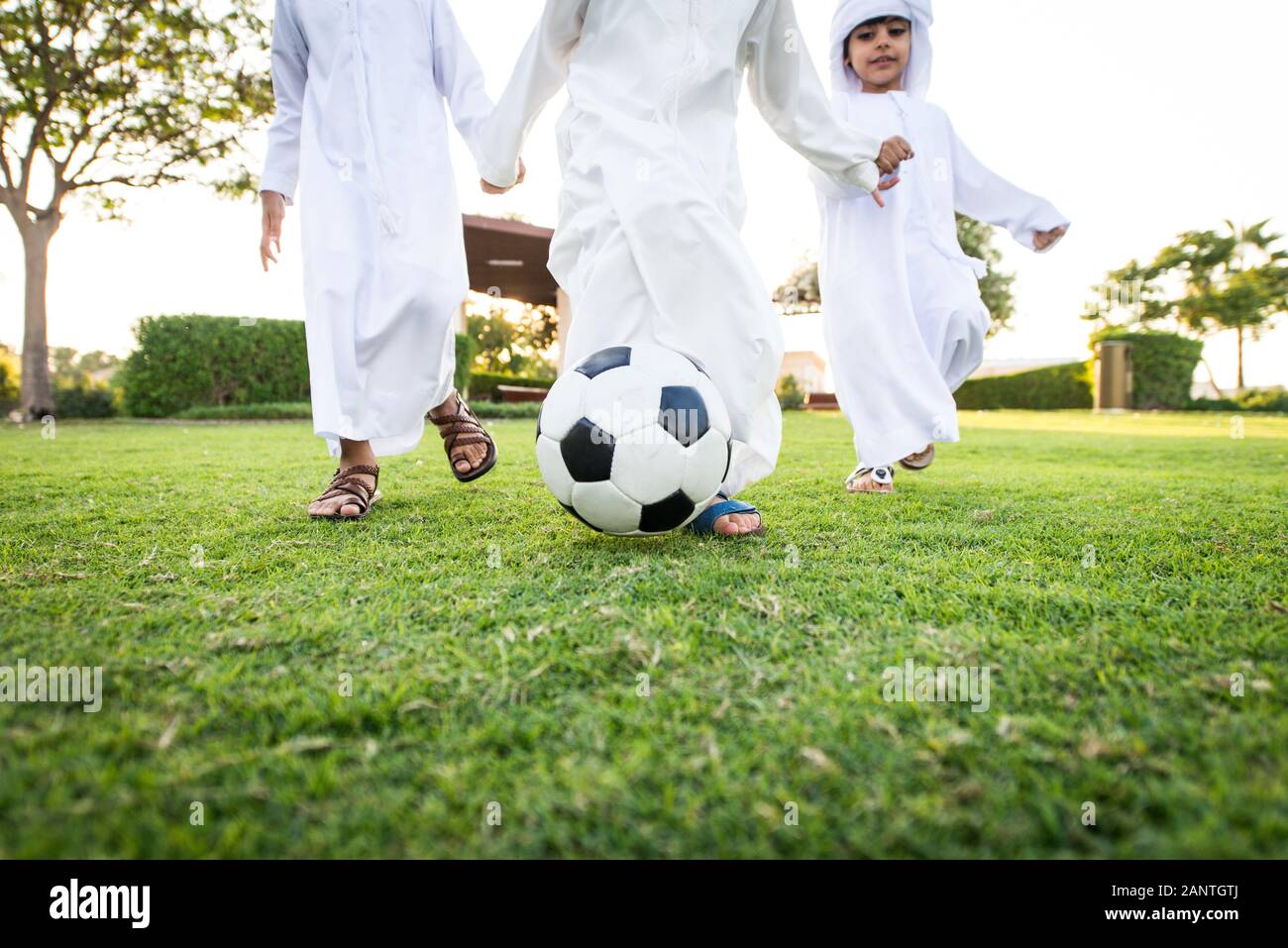 Group of middle-eastern kids wearing white kandora playing in a park in ...