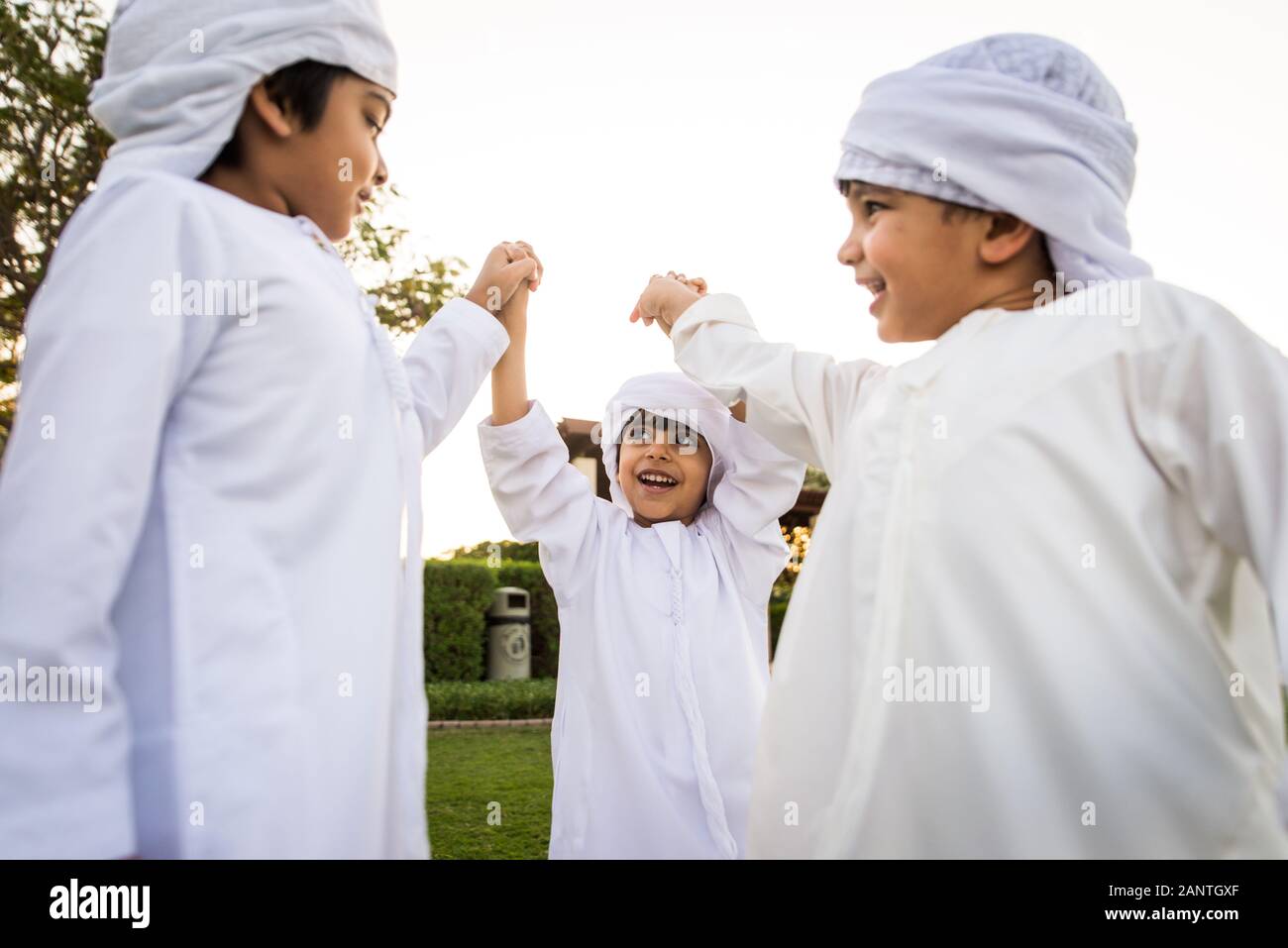 Group of middle-eastern kids wearing white kandora playing in a park in ...
