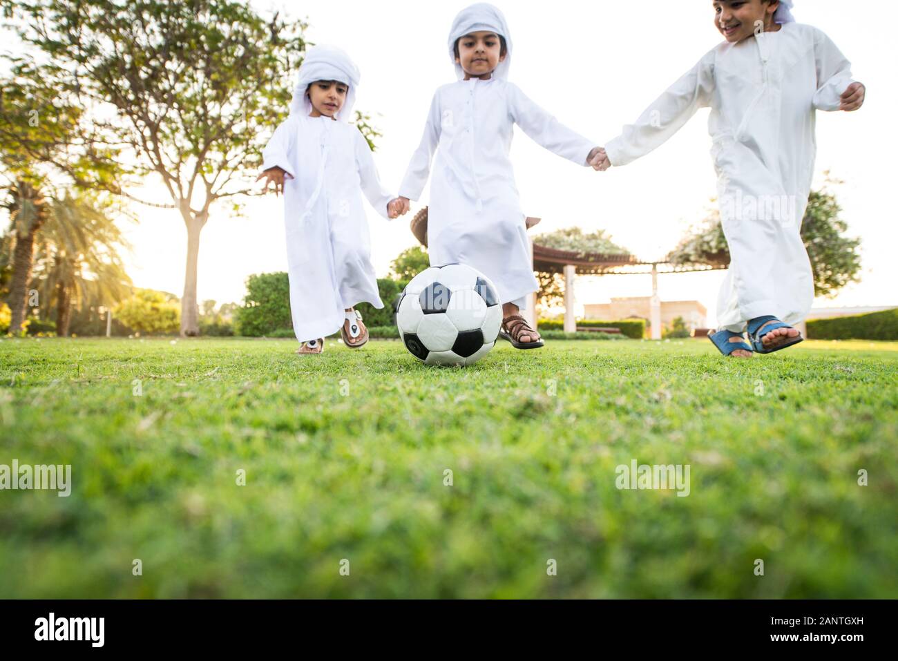 Group of middle-eastern kids wearing white kandora playing in a park in ...