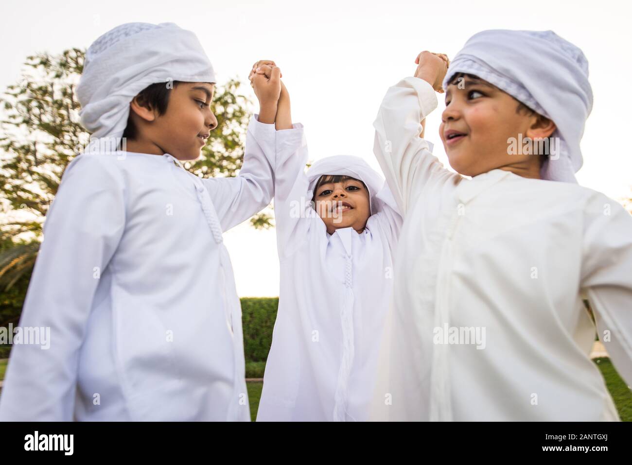 Group of middle-eastern kids wearing white kandora playing in a park in ...