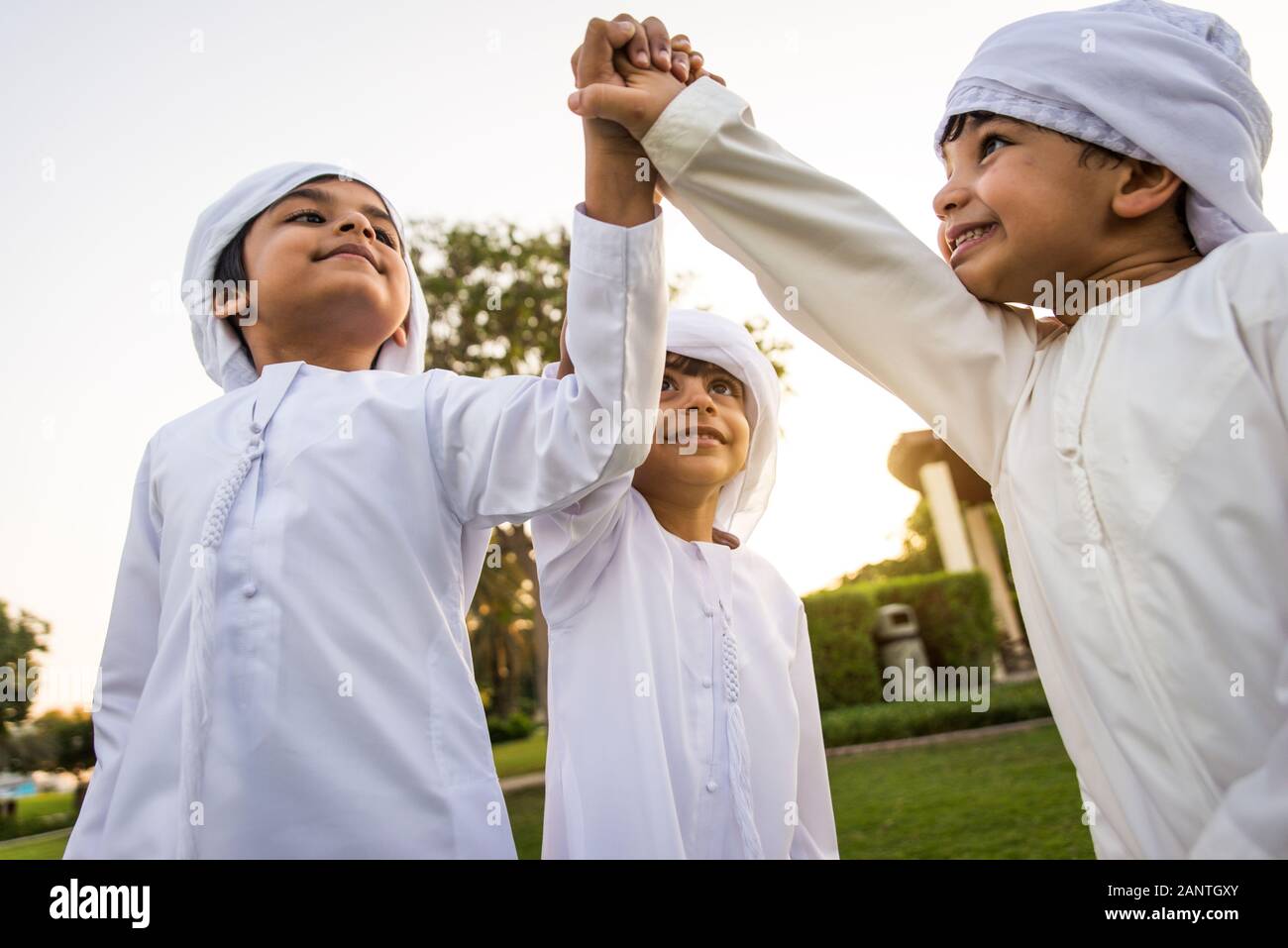 Group of middle-eastern kids wearing white kandora playing in a park in ...