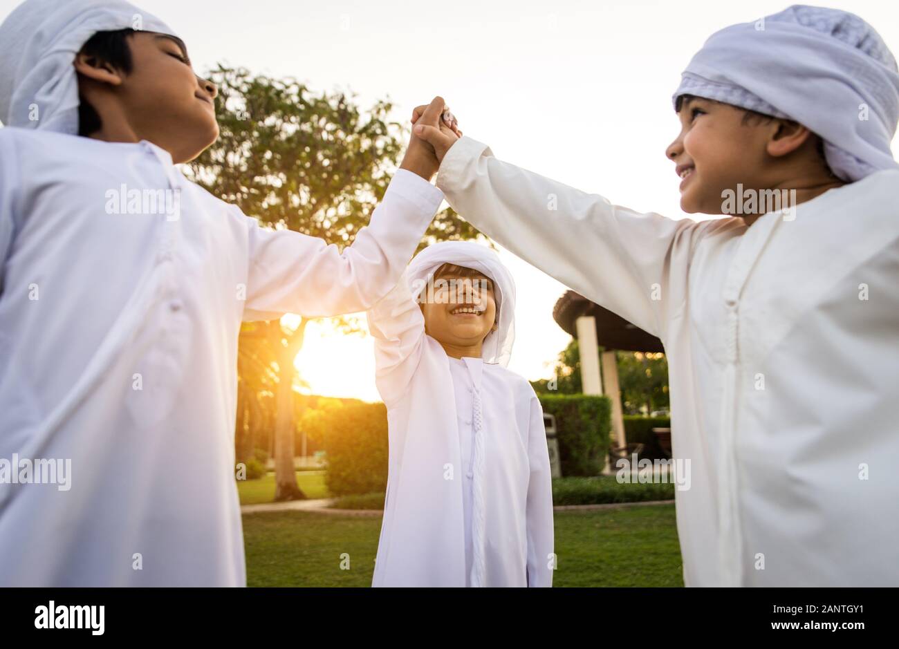 Group of middle-eastern kids wearing white kandora playing in a park in ...