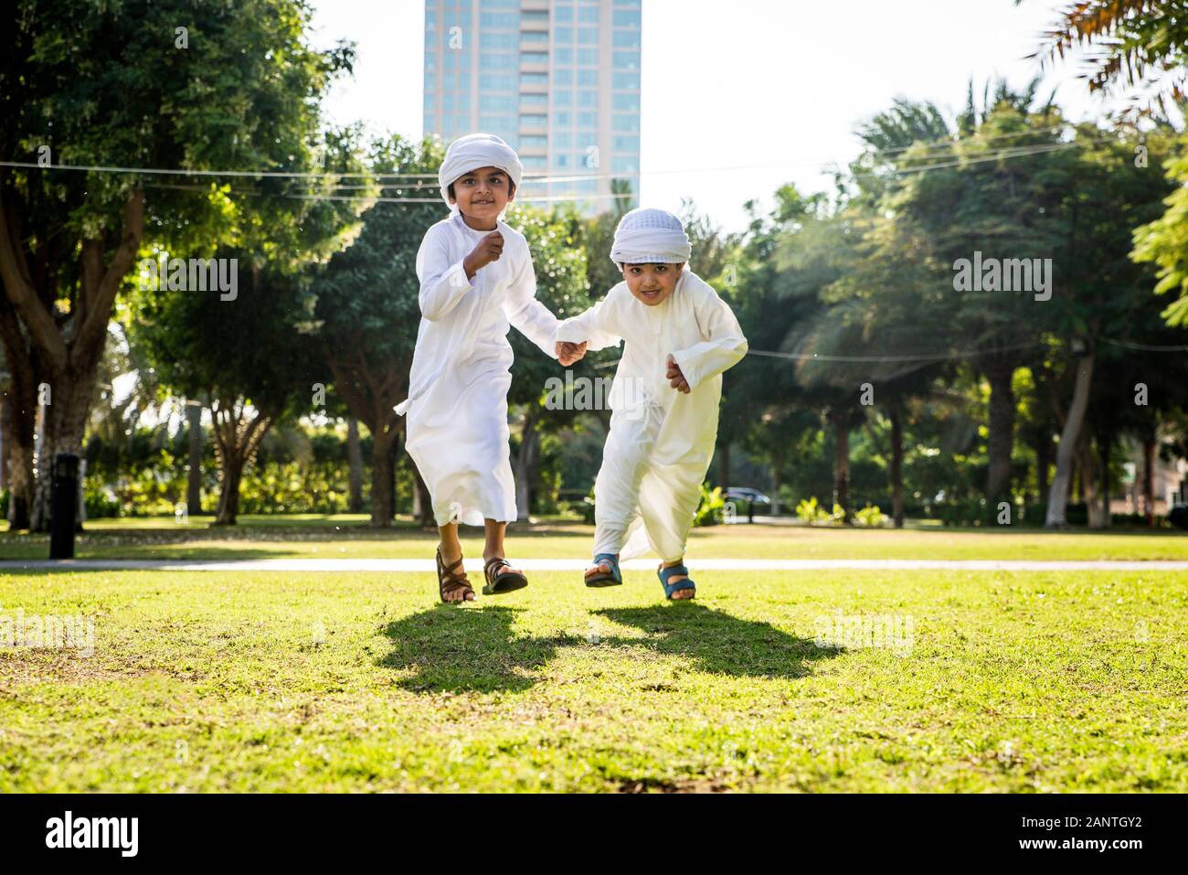 Group of middle-eastern kids wearing white kandora playing in a park in ...