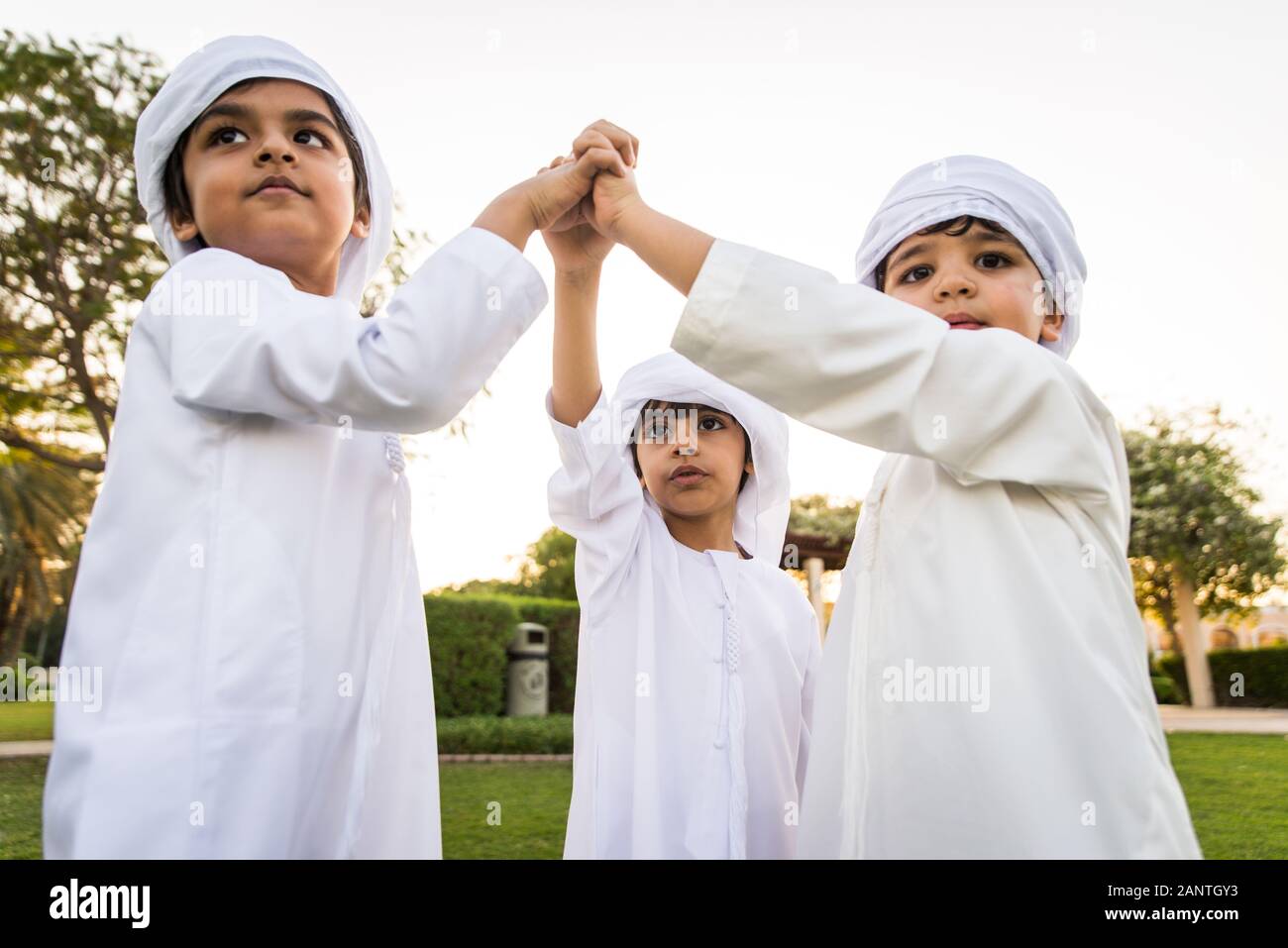 Group of middle-eastern kids wearing white kandora playing in a park in ...