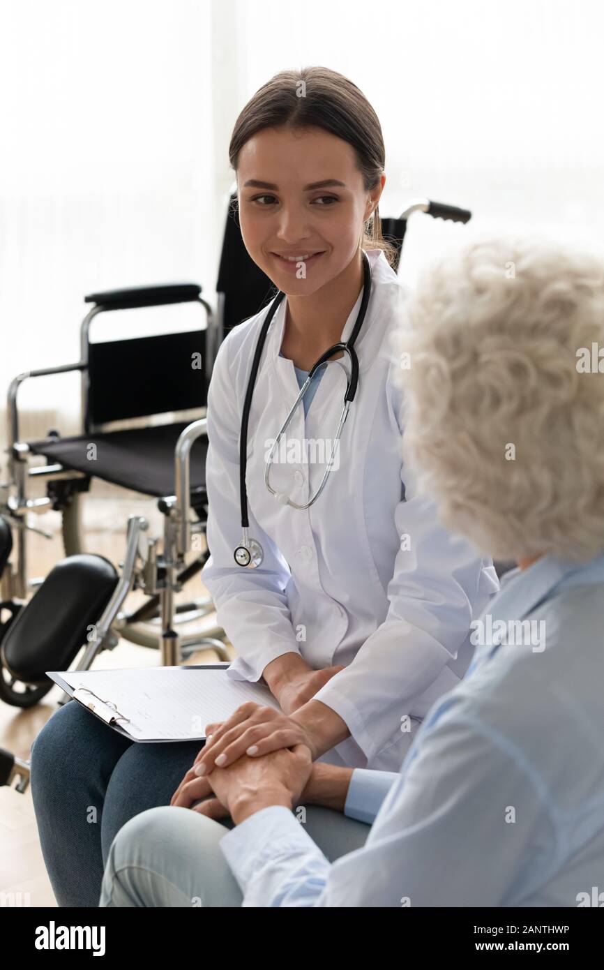 Friendly doctor supporting disabled patient during visit, holding hand ...