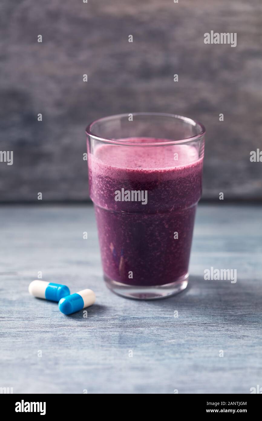 Glass of Protein Shake with milk and blueberries and Creatine capsules ...
