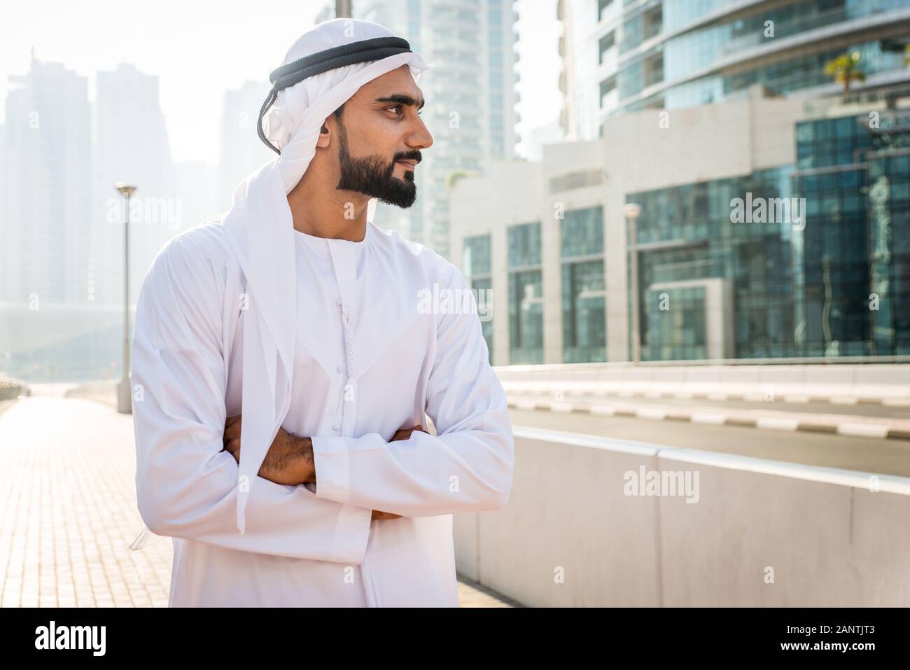 Middle-eastern young adult wearing kandora walking outdoors in Dubai ...