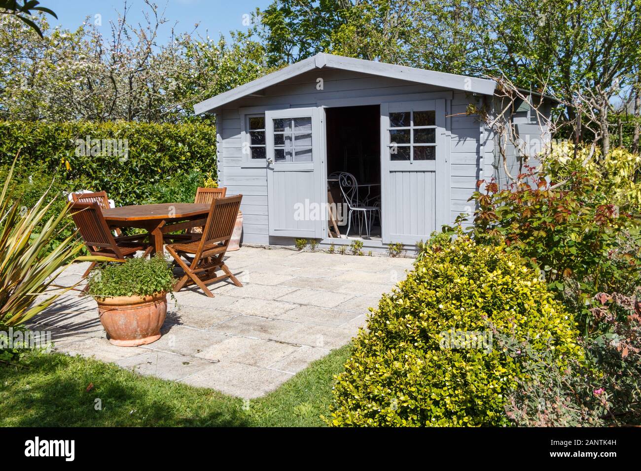 Shed with open door and terrace with wooden garden furniture during ...