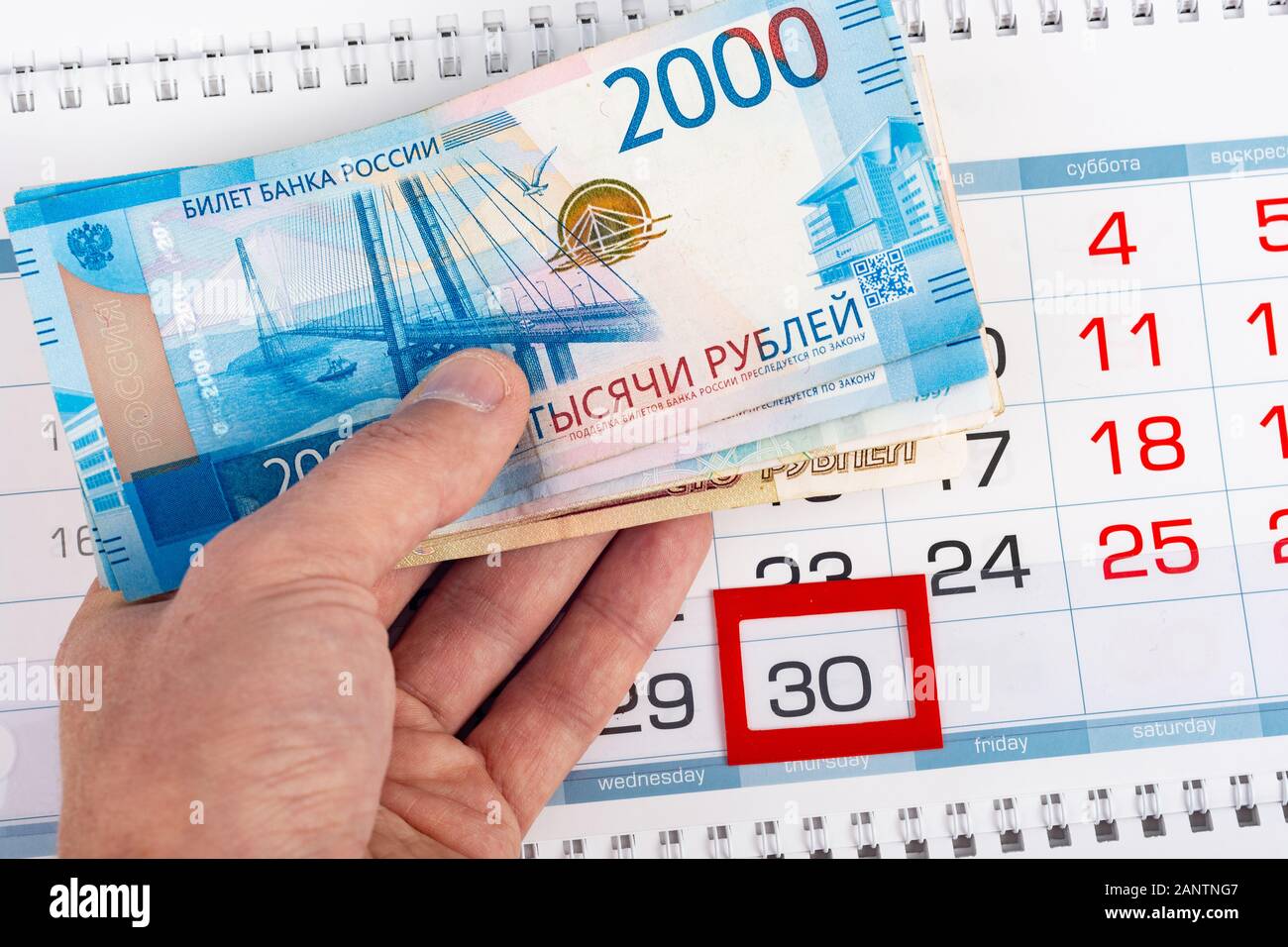 Hand holds wad of money over calendar number 30 Stock Photo - Alamy