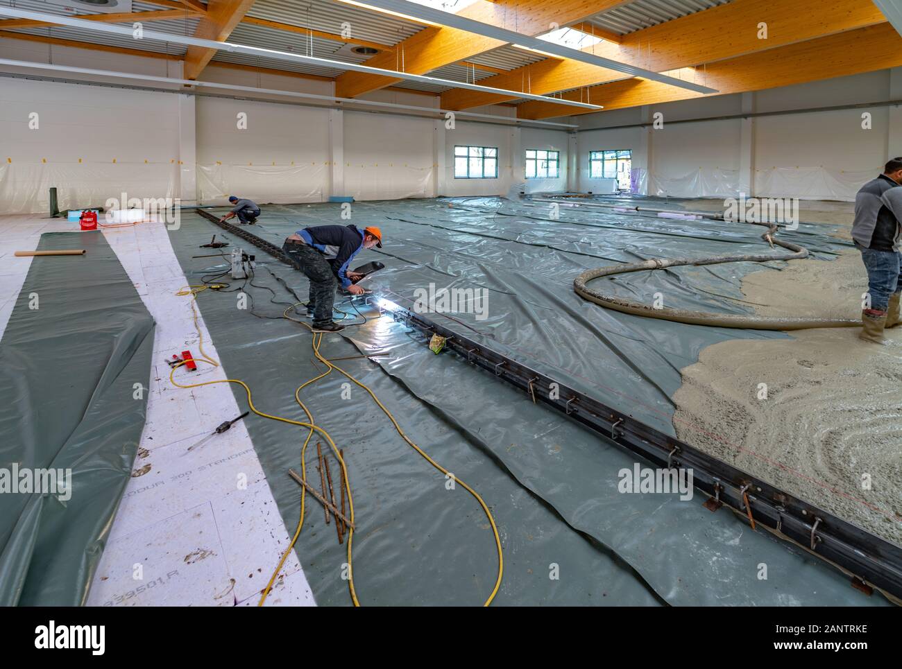 the screed is poured on a construction site inside a large factory ...