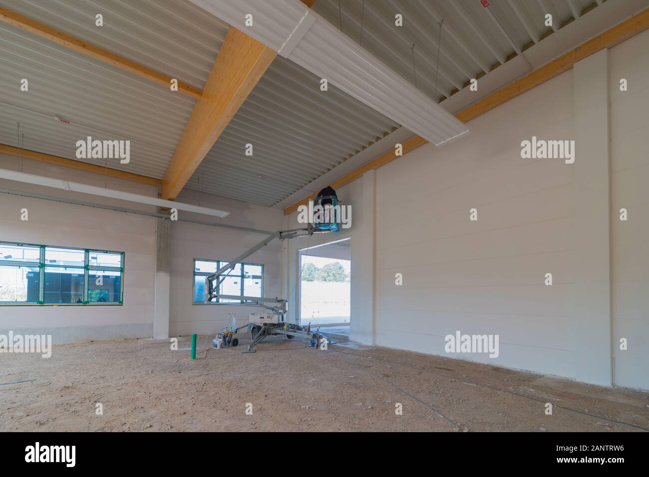 Inside a large factory building, the walls are sprayed white by a ...