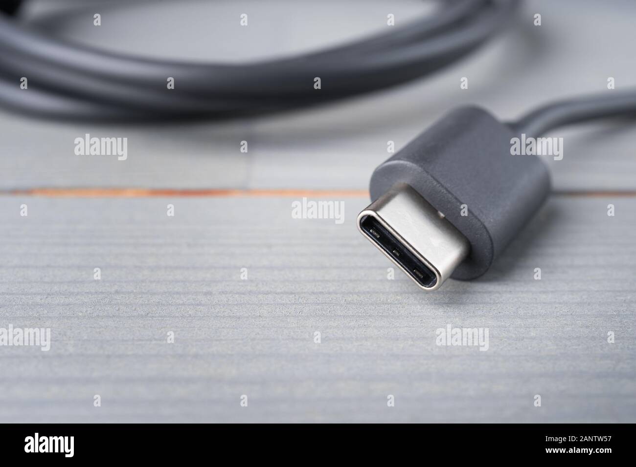 USB Type C connector with a grey cable on a wooden background. Shallow ...