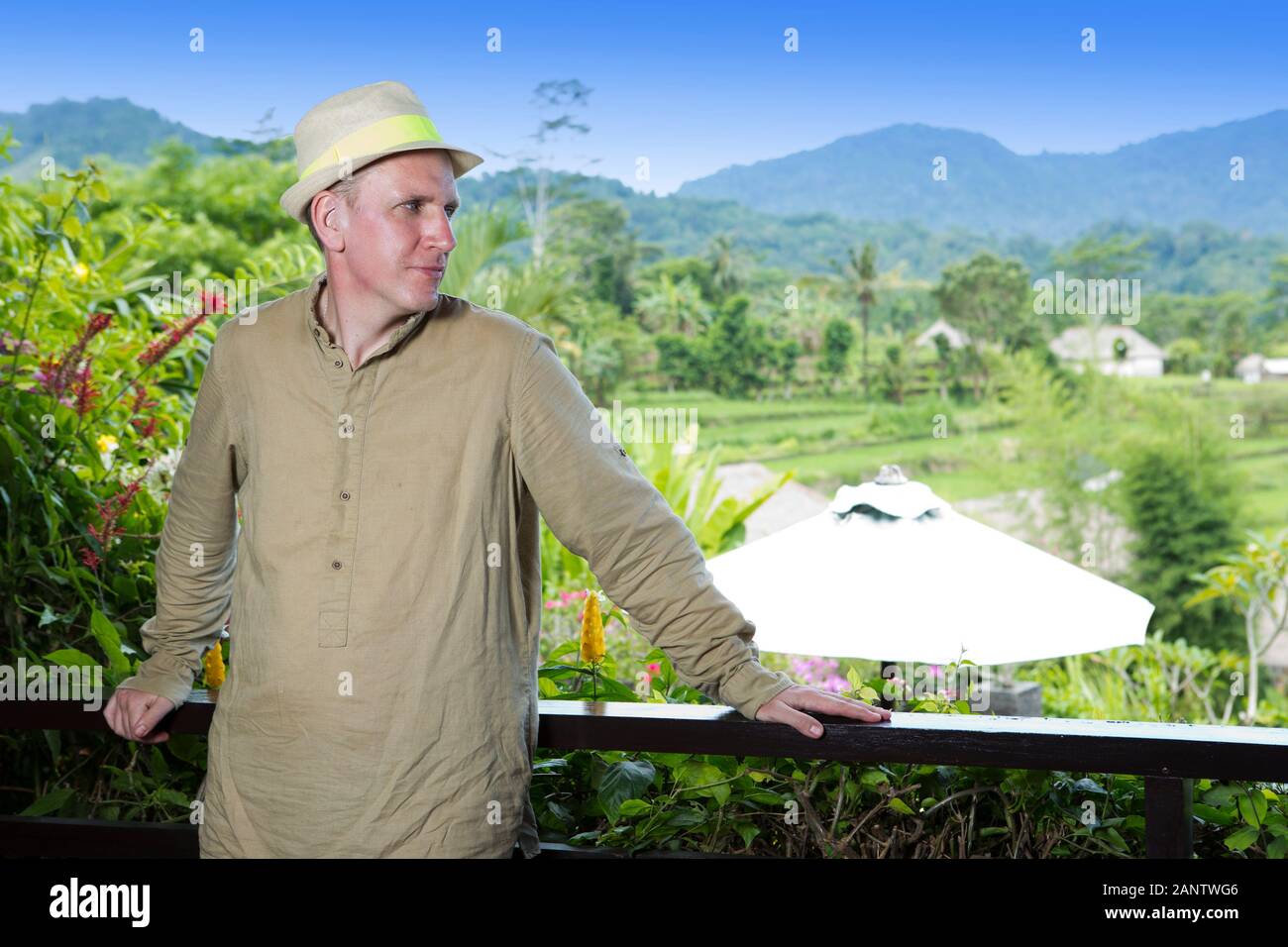 mature man in summer clothes and a sun hat on the veranda looks at the ...