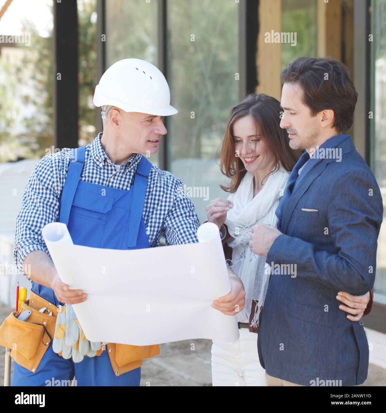 Foreman showing house design construction plan to a happy young couple ...