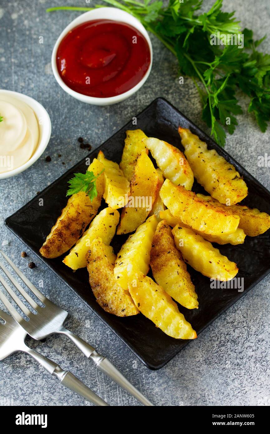 Fast food. Baked potatoes with spices, slices on slate or stone, served ...