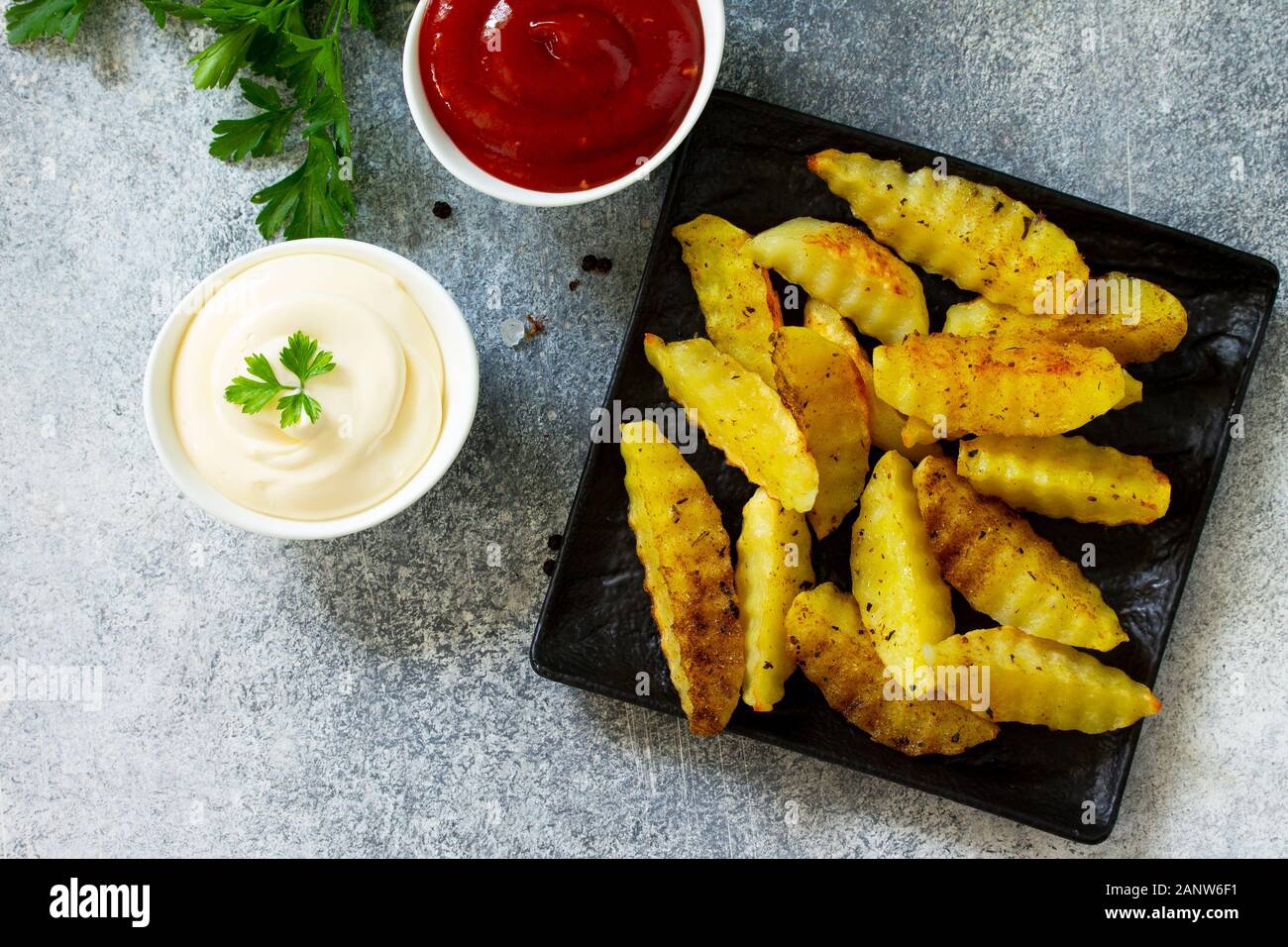 Fast food. Baked potatoes with spices, slices on slate or stone, served ...