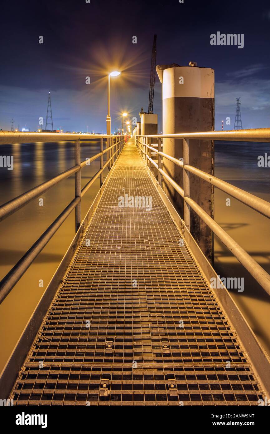 Illuminated pier on large steel mooring posts Stock Photo - Alamy