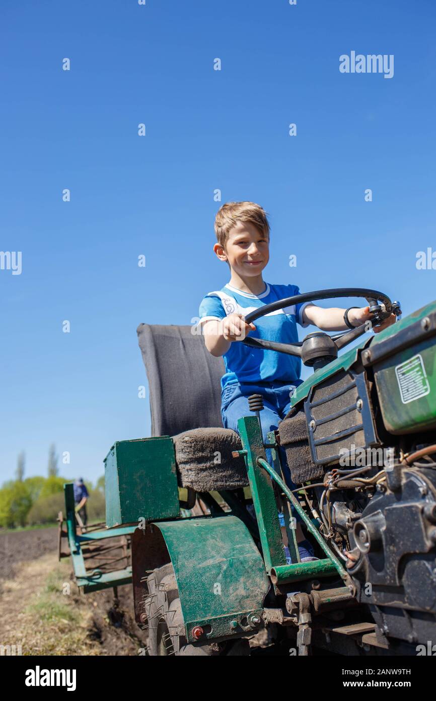 Small happy boy trying to drive farm tractor on the field Stock Photo ...