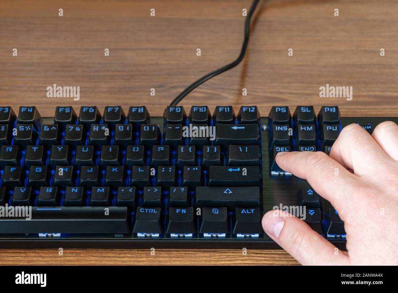 index finger of a male hand presses the delete key on a black keyboard ...