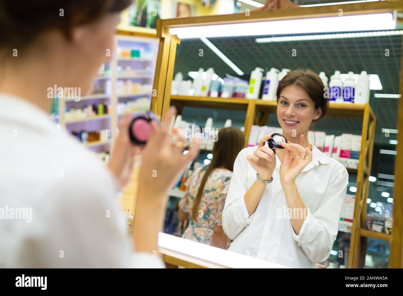 Beautiful girl chooses cosmetics in the store, try on it and thinks ...