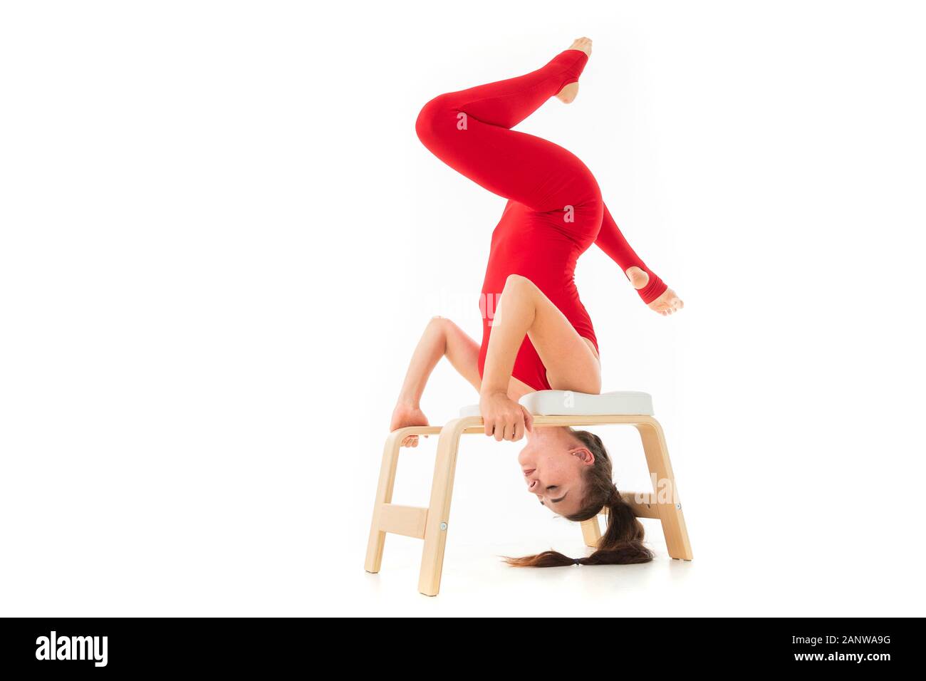 Caucasian gymnast with athletic body stands on her head, does warm-up ...