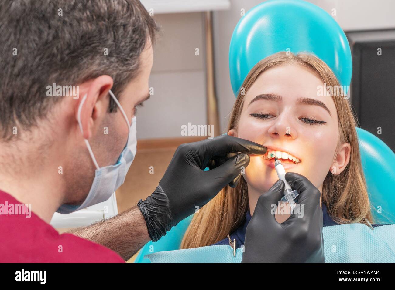 doctor applies a blue medicine to the patient tooth with a syringe ...