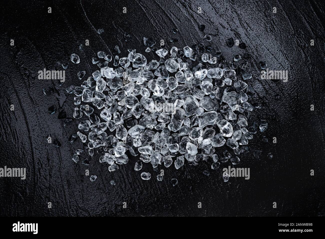 Pile of crushed ice cubes on black stone background, top view with copy ...