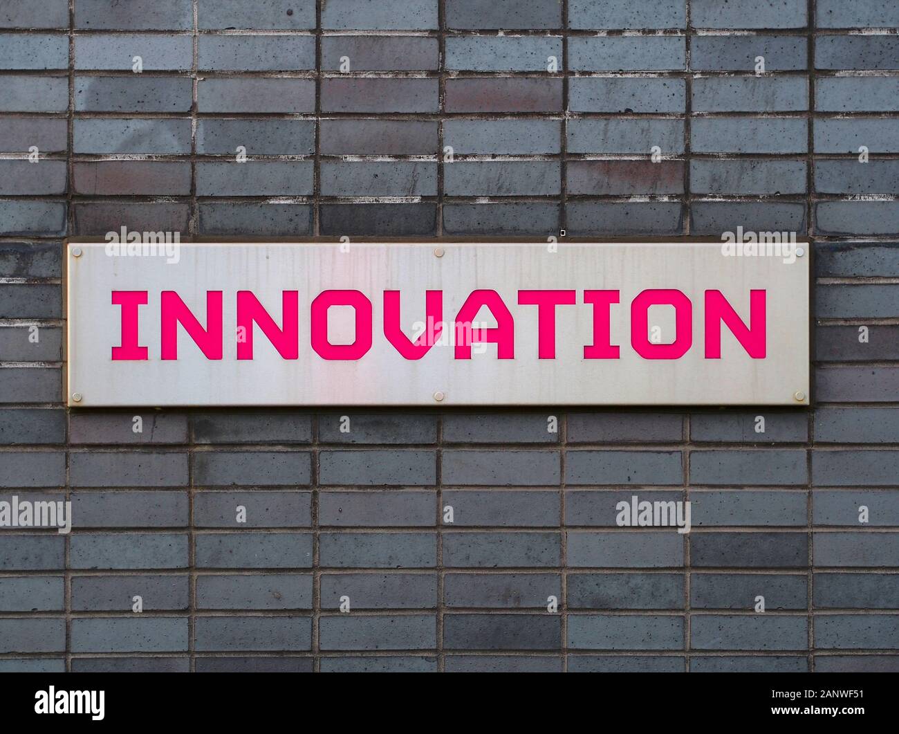 Innovation sign with colourful pink lettering set against a blue brick ...