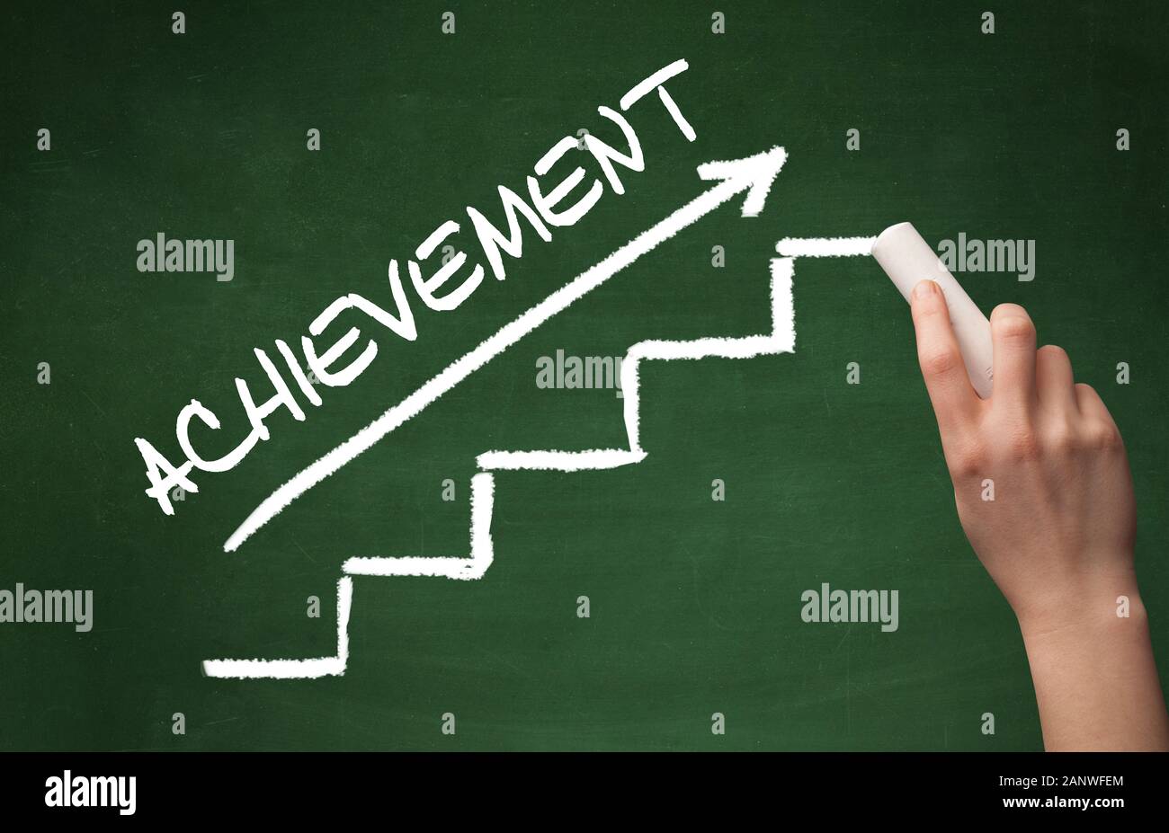 Hand drawing ACHIEVEMENT inscription with white chalk on blackboard ...